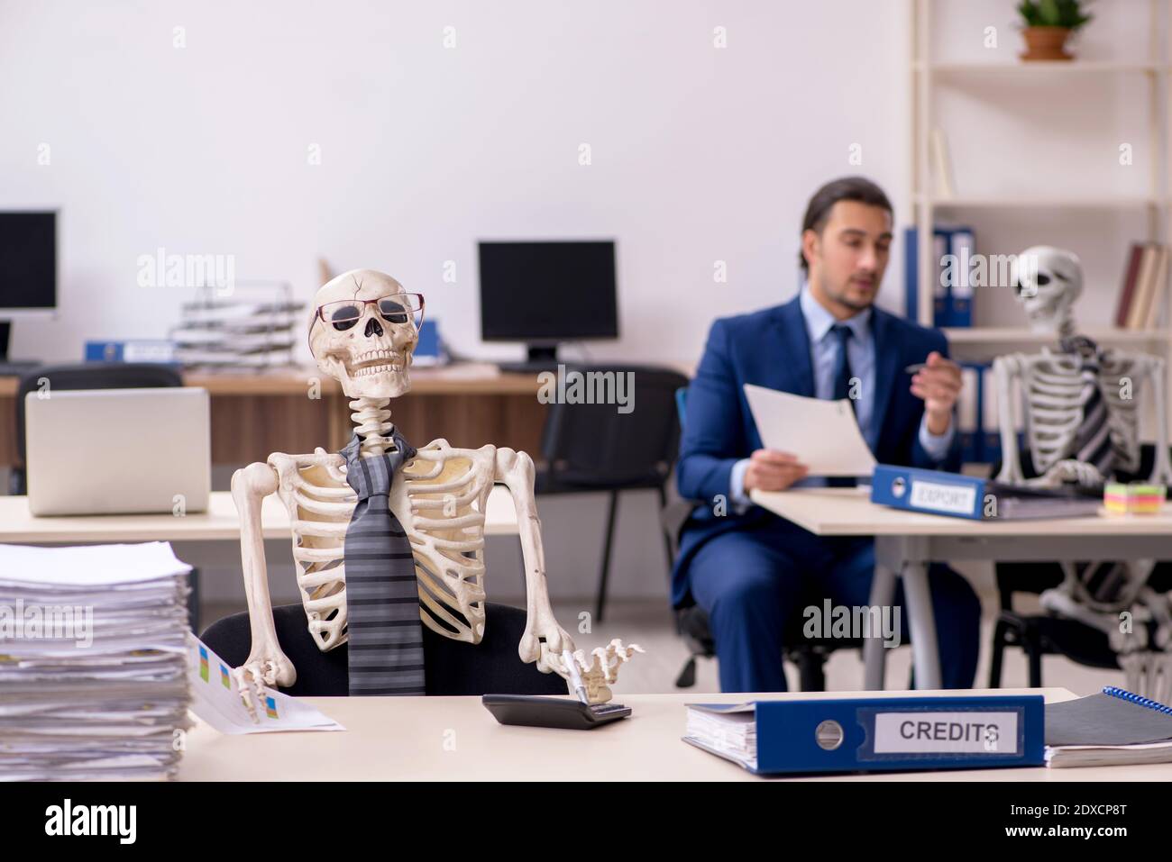 Young employee with skeletons in the office Stock Photo - Alamy