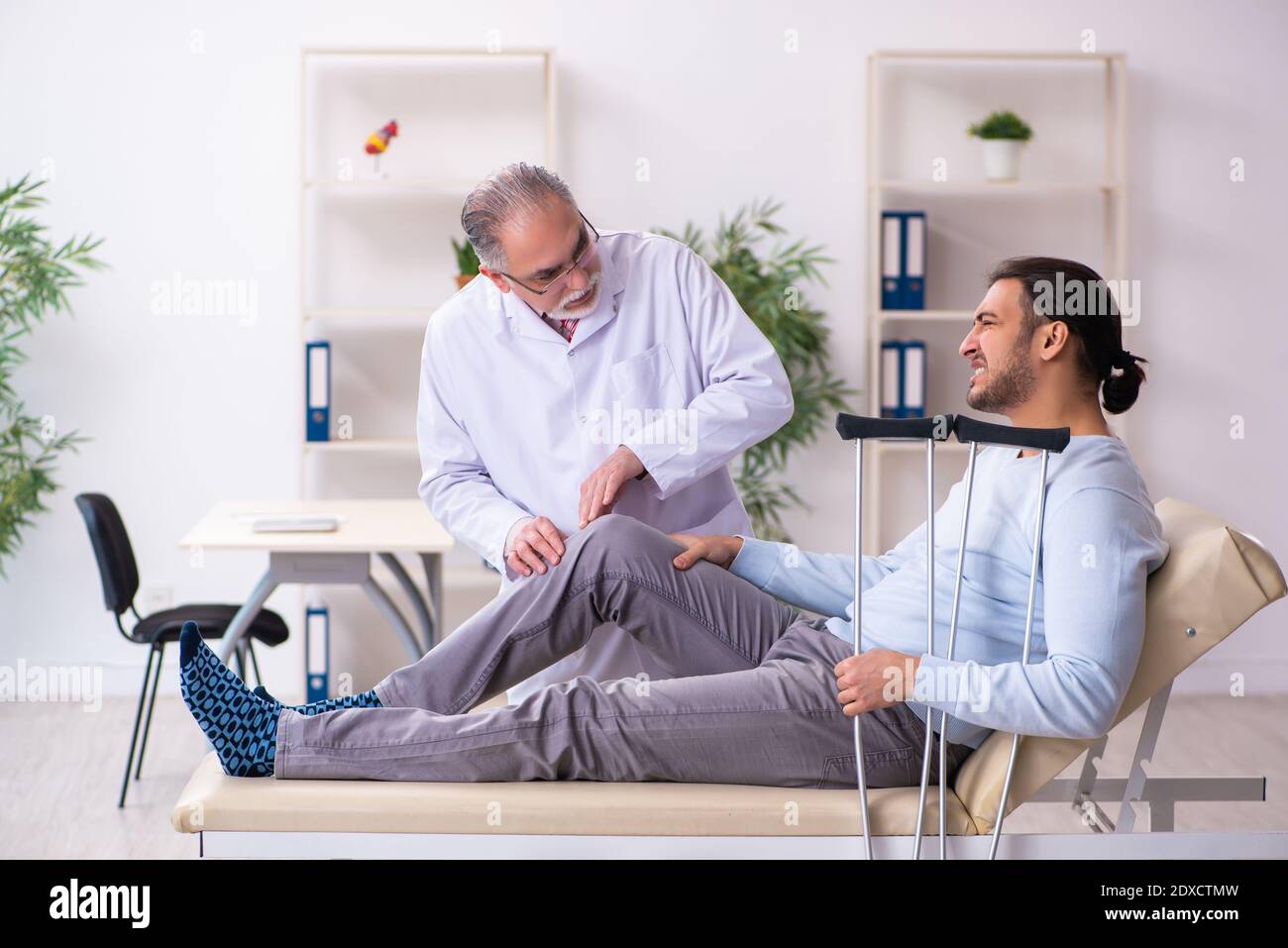 Leg injured man visiting old doctor osteopath Stock Photo - Alamy