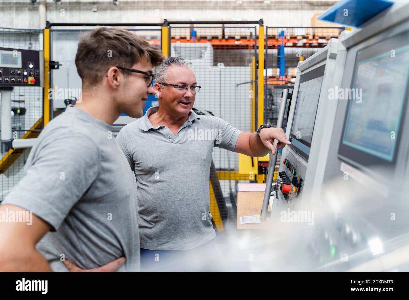 Male engineers brainstorming while testing machine at factory Stock ...