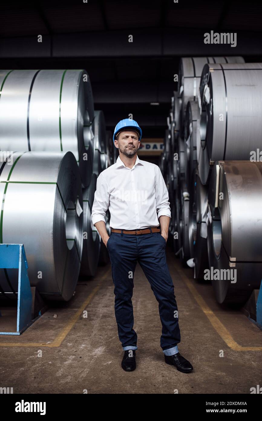 Confident male owner with hands in pockets standing in factory Stock ...