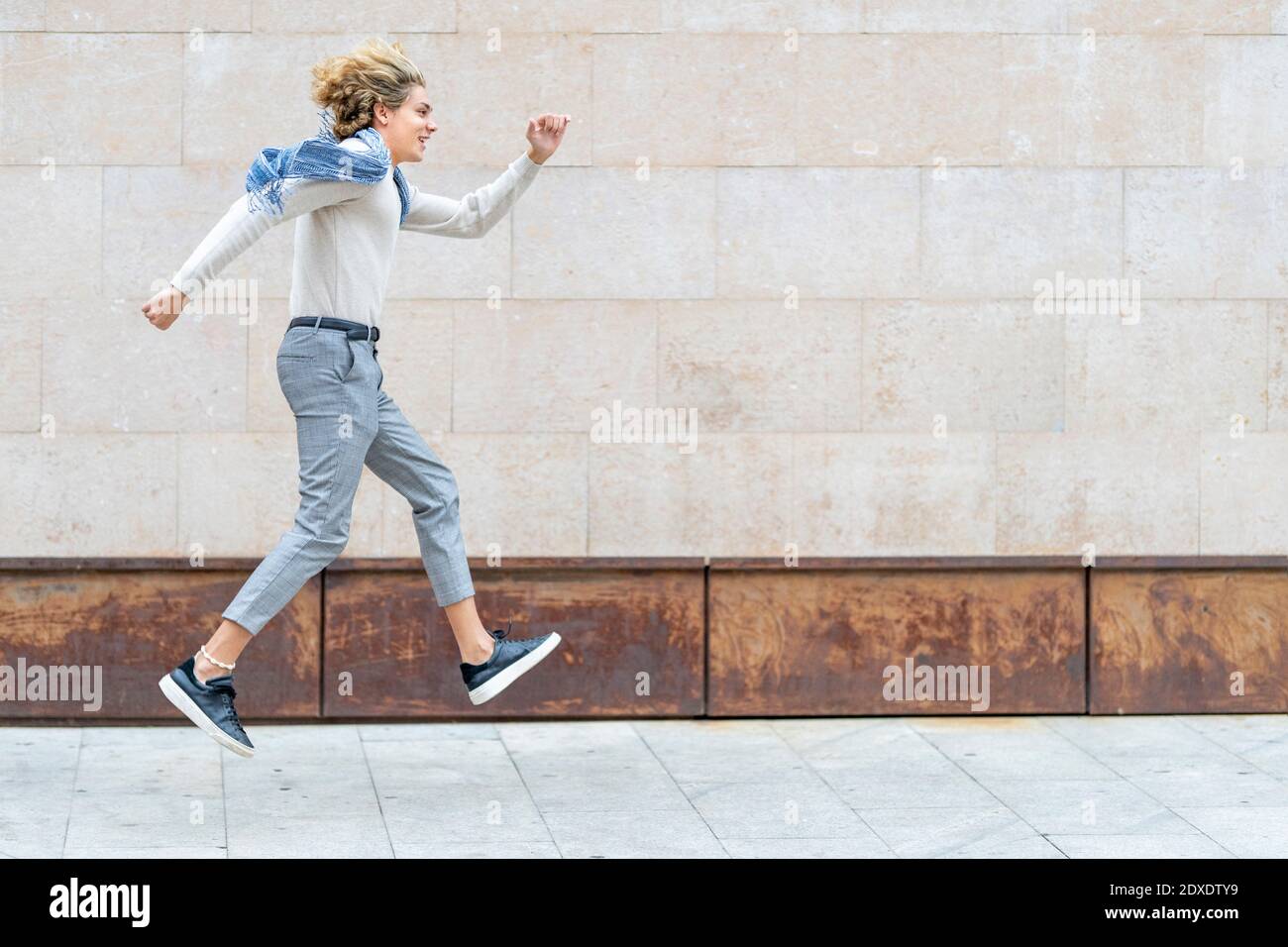 Carefree man walking on footpath against wall Stock Photo - Alamy