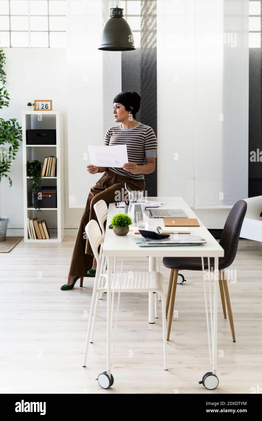 Businesswoman browsing documents at edge of office table Stock Photo ...