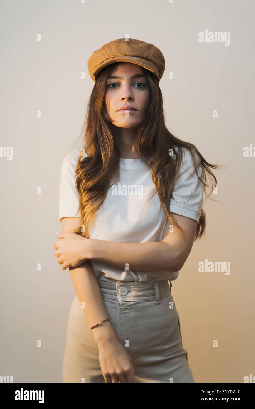 Woman wearing cap staring while standing against wall Stock Photo - Alamy