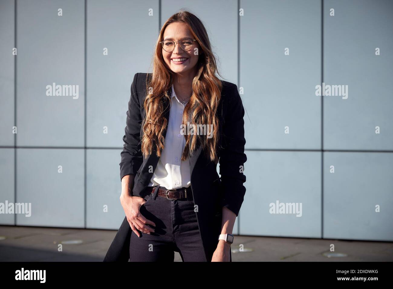 Female professional smiling while standing against wall Stock Photo - Alamy