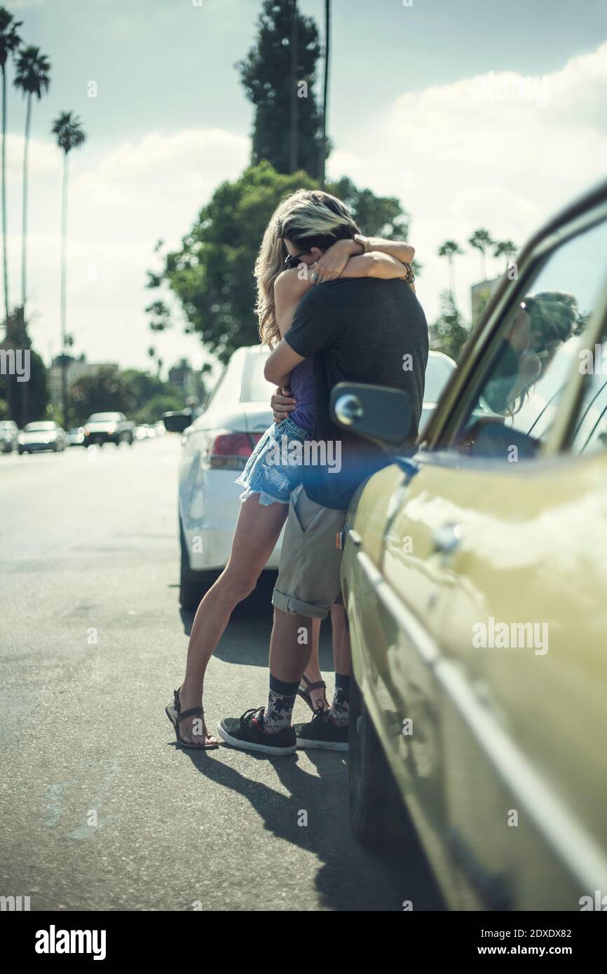Affectionate couple embracing by vintage car on street in city Stock ...