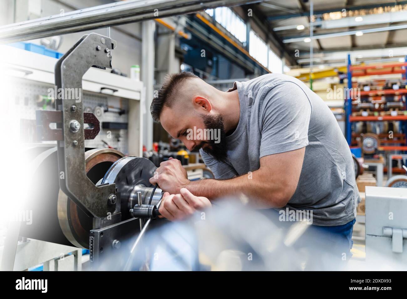 Professional male engineer fastening nut on machine in illuminated ...