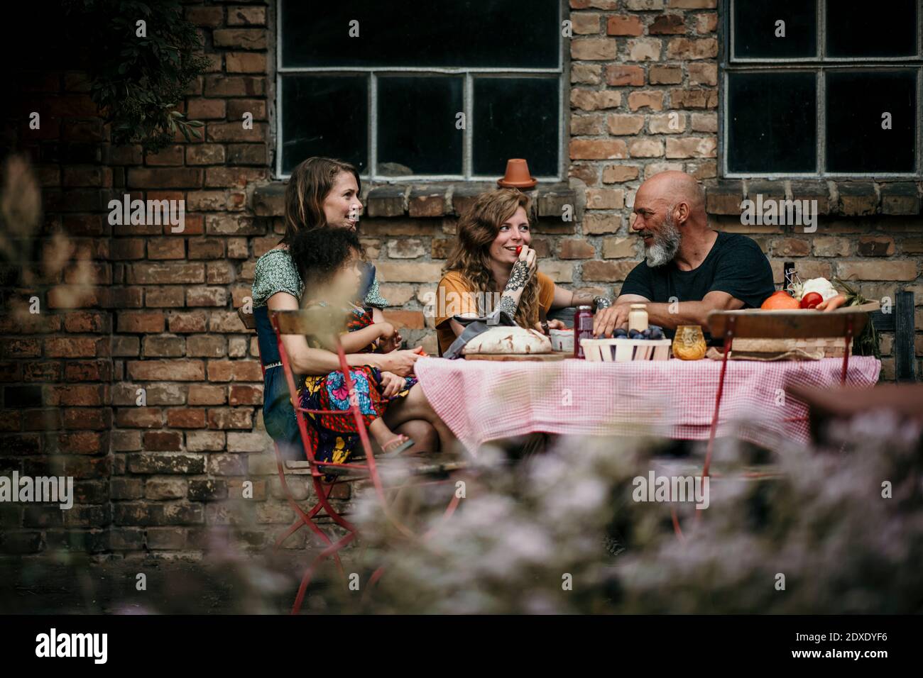 Smiling friends talking while eating vegetable at backyard Stock Photo ...