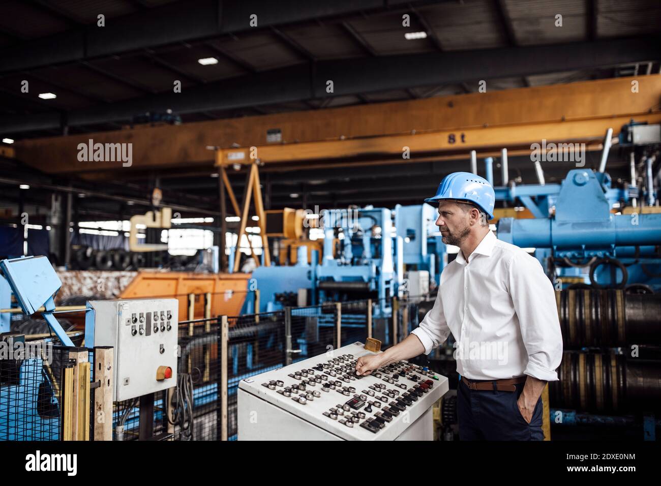 Businessman operating control panel with hand in pocket standing at ...
