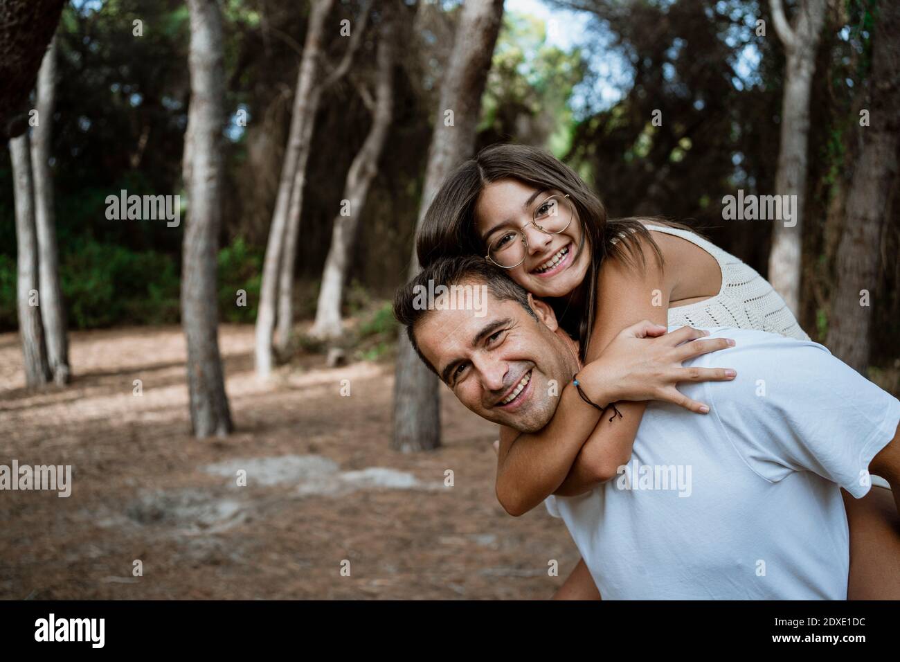 Happy father giving piggyback to daughter in forest Stock Photo - Alamy