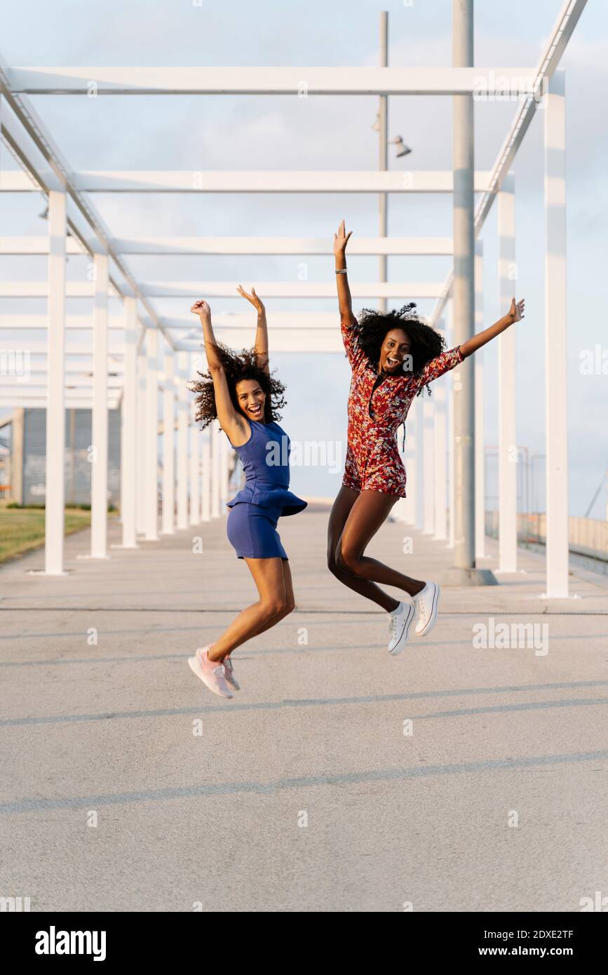Happy female friends jumping Stock Photo - Alamy