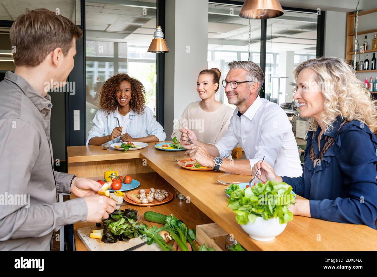 Smiling business people having food on kitchen counter in office Stock ...