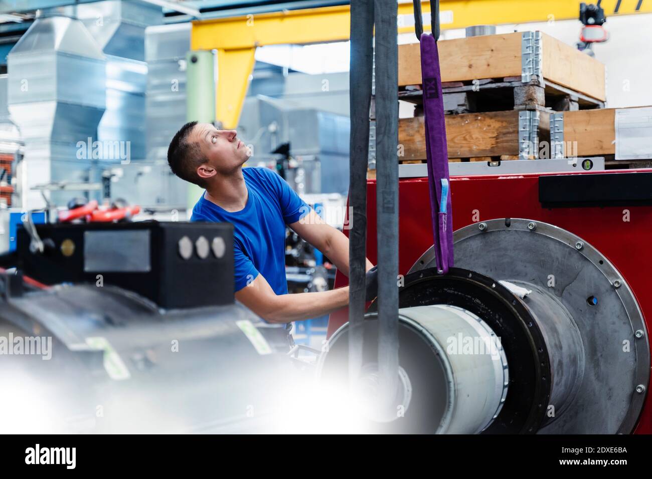 Male manual worker looking up while standing by machine at industry ...