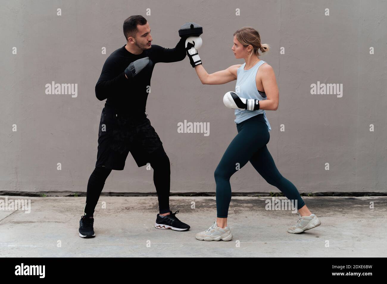 Couple practicing boxing while standing against wall Stock Photo - Alamy