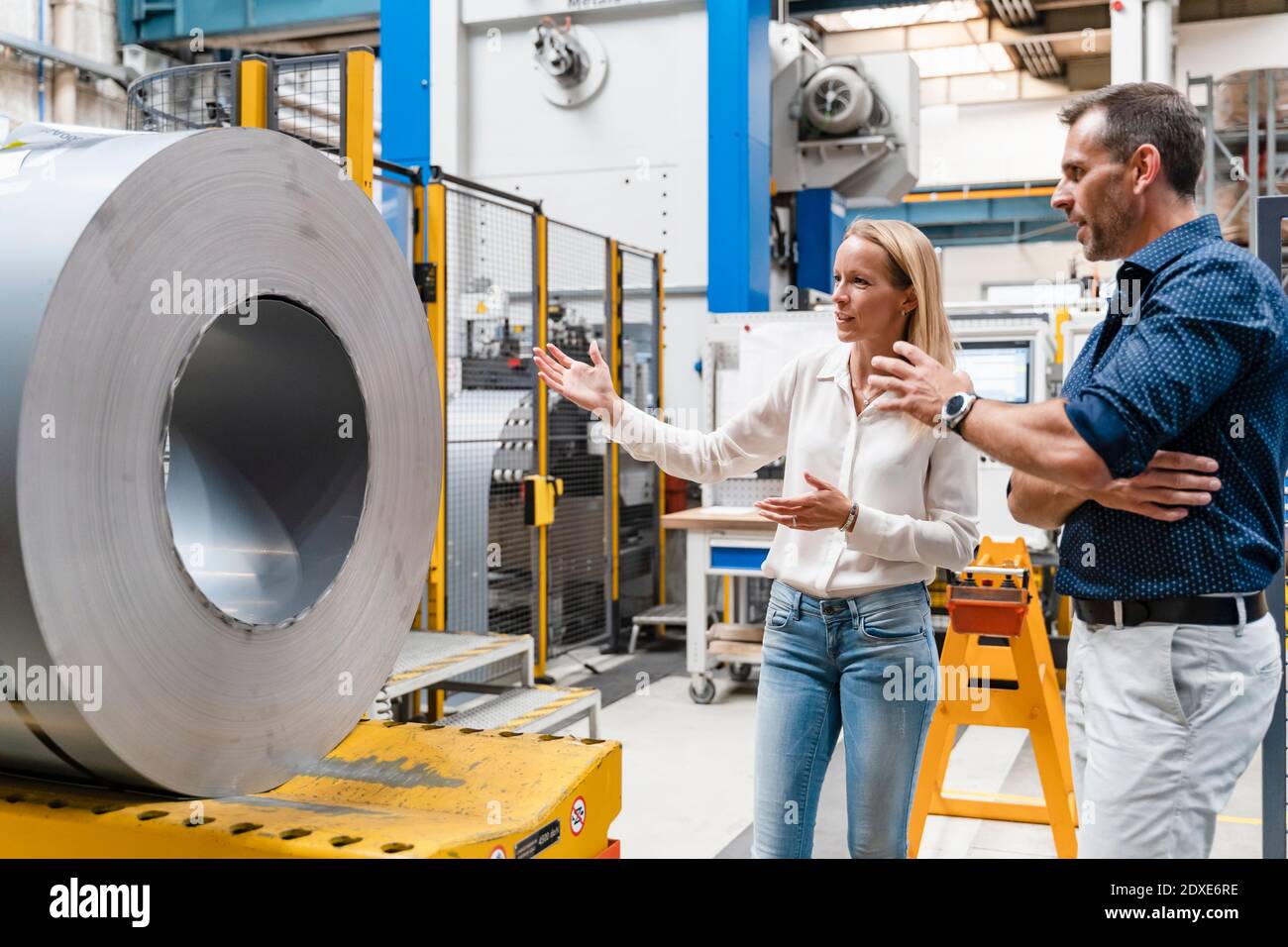 Female entrepreneur and male colleague examining steel roll while ...