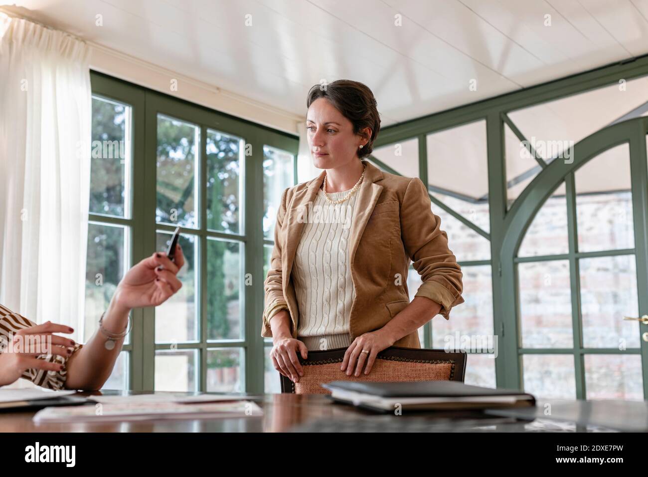Businesswoman giving USB stick to female colleague standing while ...