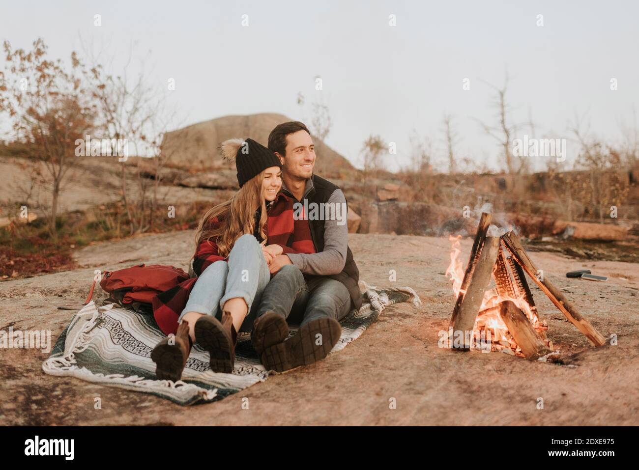 Young couple sitting together in front of campfire Stock Photo - Alamy