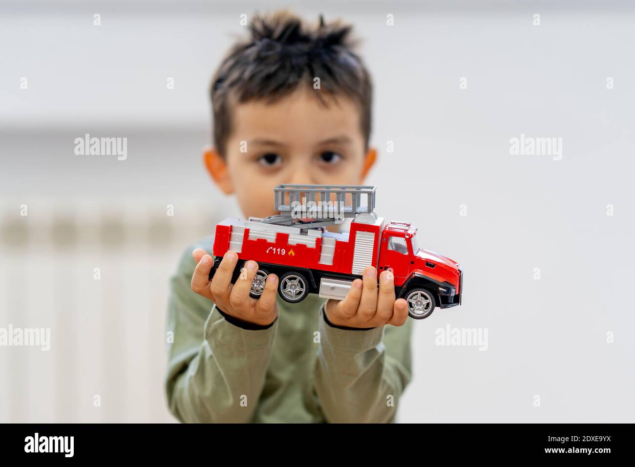 Cute boy holding fire engine toy at home Stock Photo - Alamy