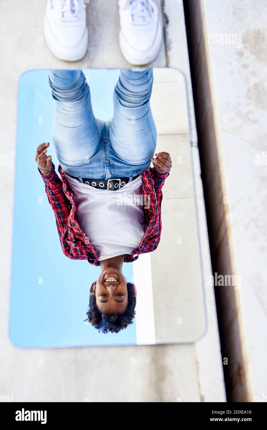 Cheerful young Afro woman reflecting on mirror Stock Photo - Alamy