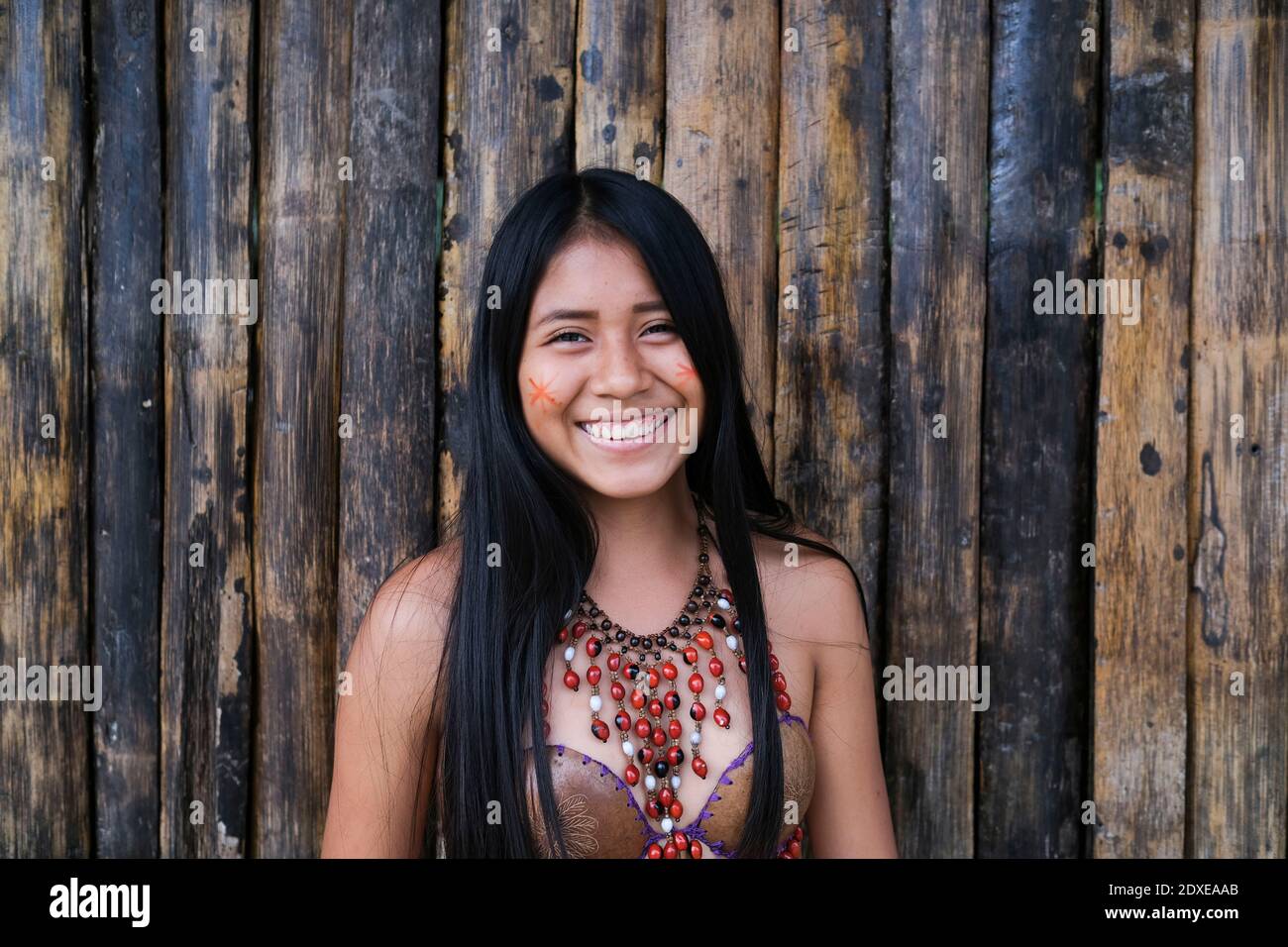 Happy young Guarani woman against bamboo wall, Misahualli, Ecuador ...