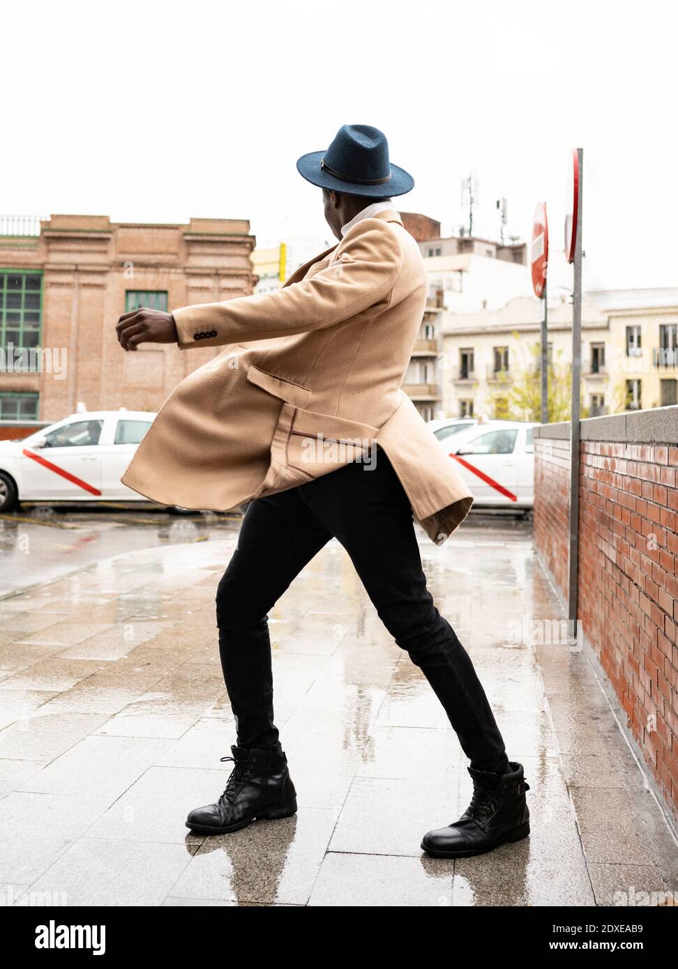 Man wearing hat and blazer spinning while standing on rooftop Stock ...