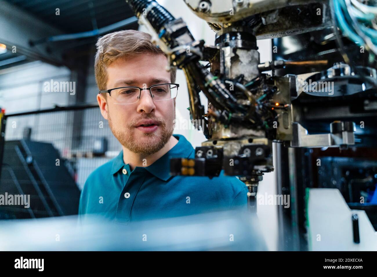 Male manual worker analyzing robotic arm at manufacturing industry ...