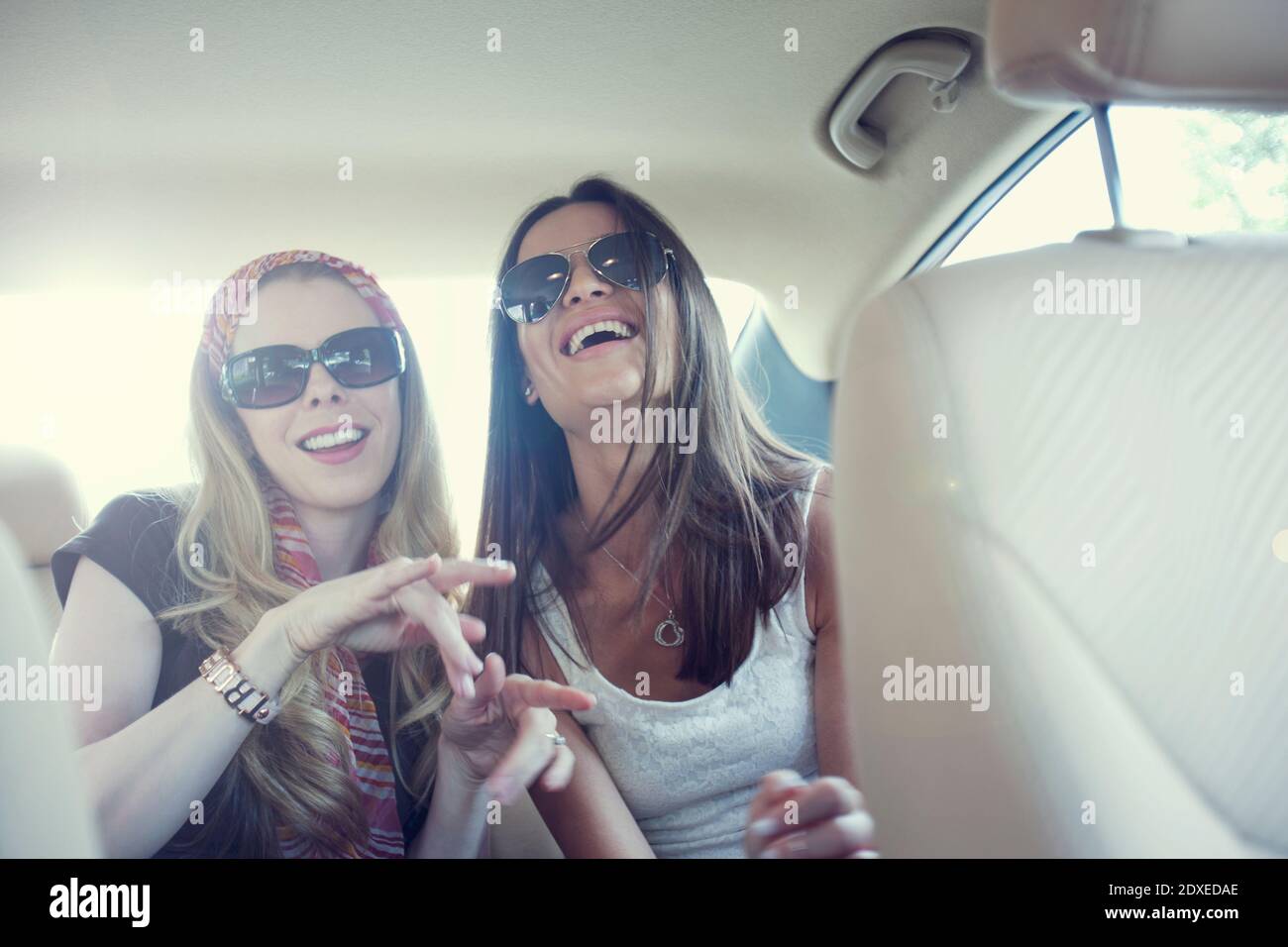 Cheerful female friends dancing in back seat of car during road trip ...