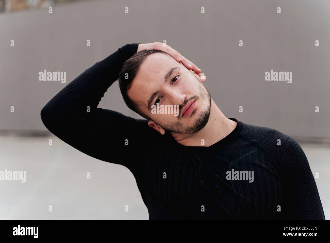 Man stretching head while standing against wall Stock Photo - Alamy