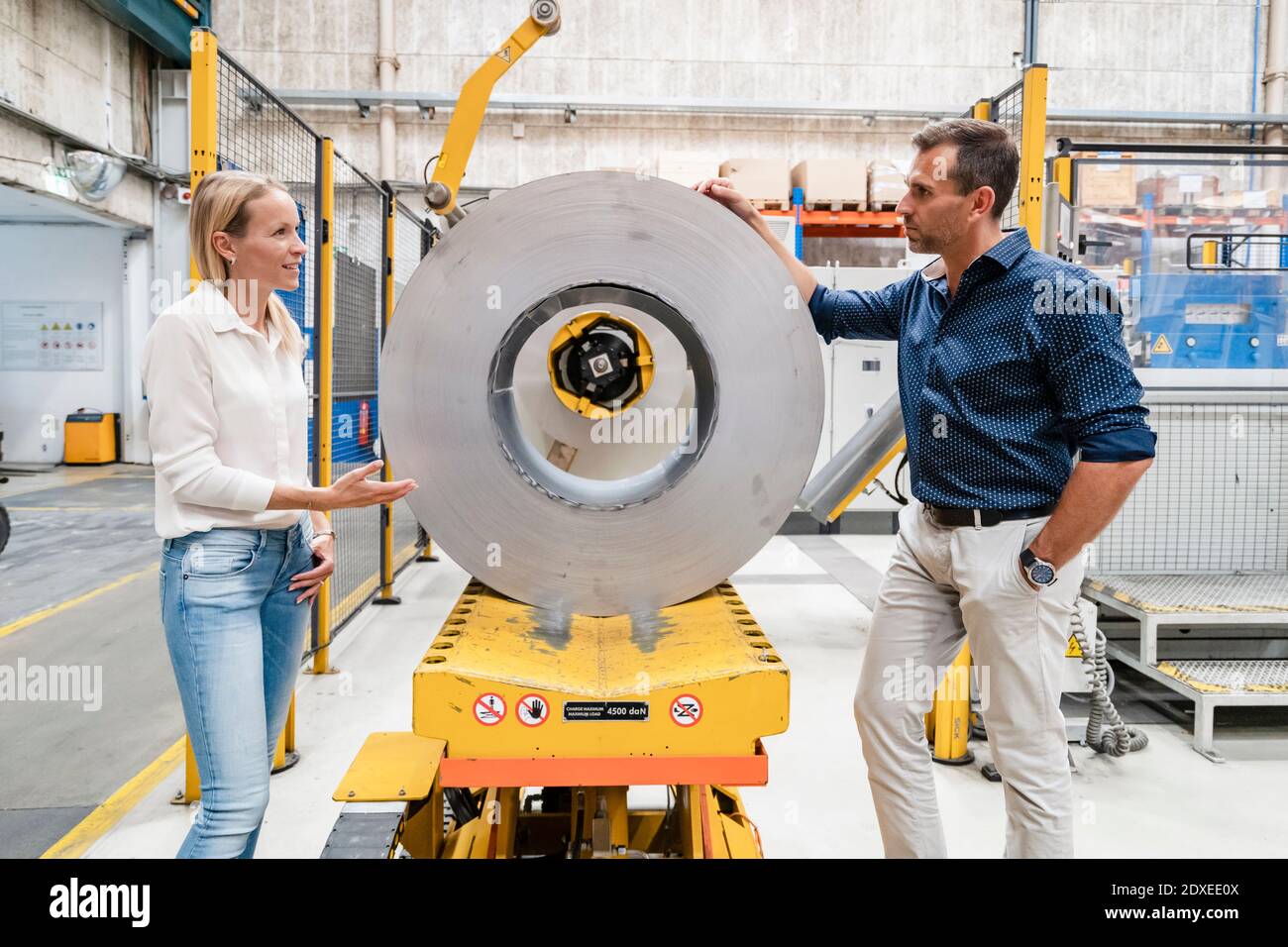 Female entrepreneur discussing about steel roll with male colleague ...