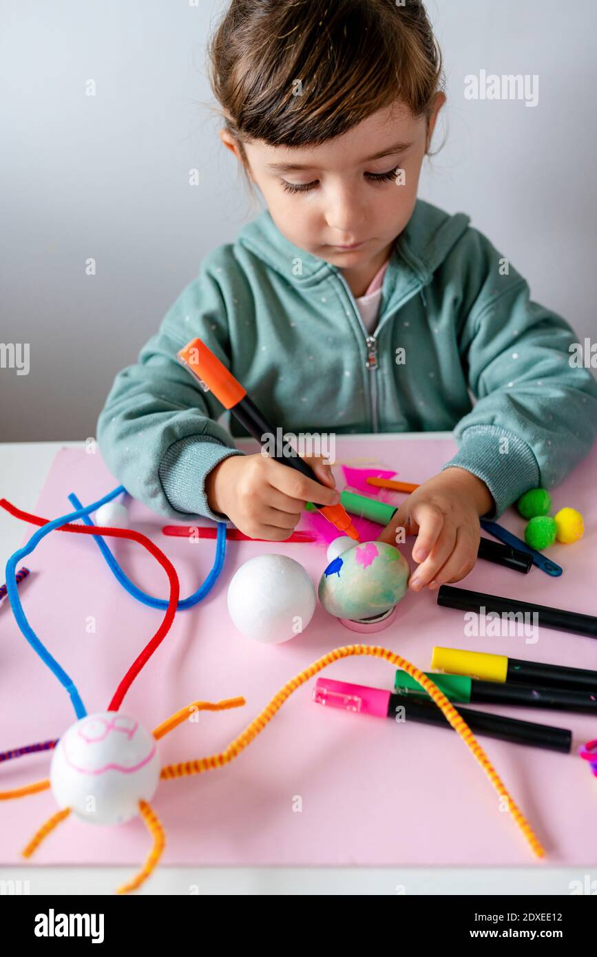 Girl coloring styrofoam ball with sketch pen on table Stock Photo - Alamy
