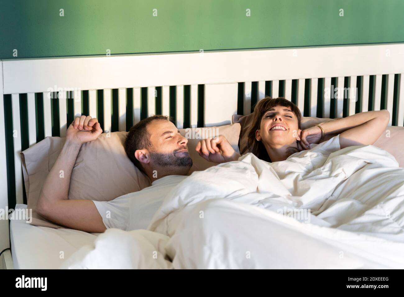 Man and woman waking up slowly while lying on bed at home Stock Photo ...