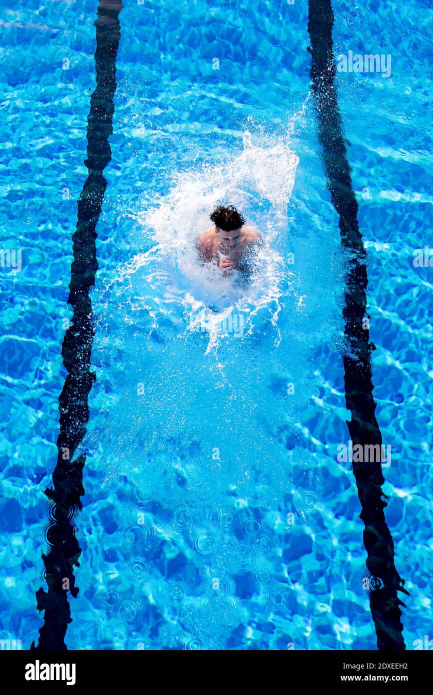 Young man splashing water in swimming pool Stock Photo - Alamy