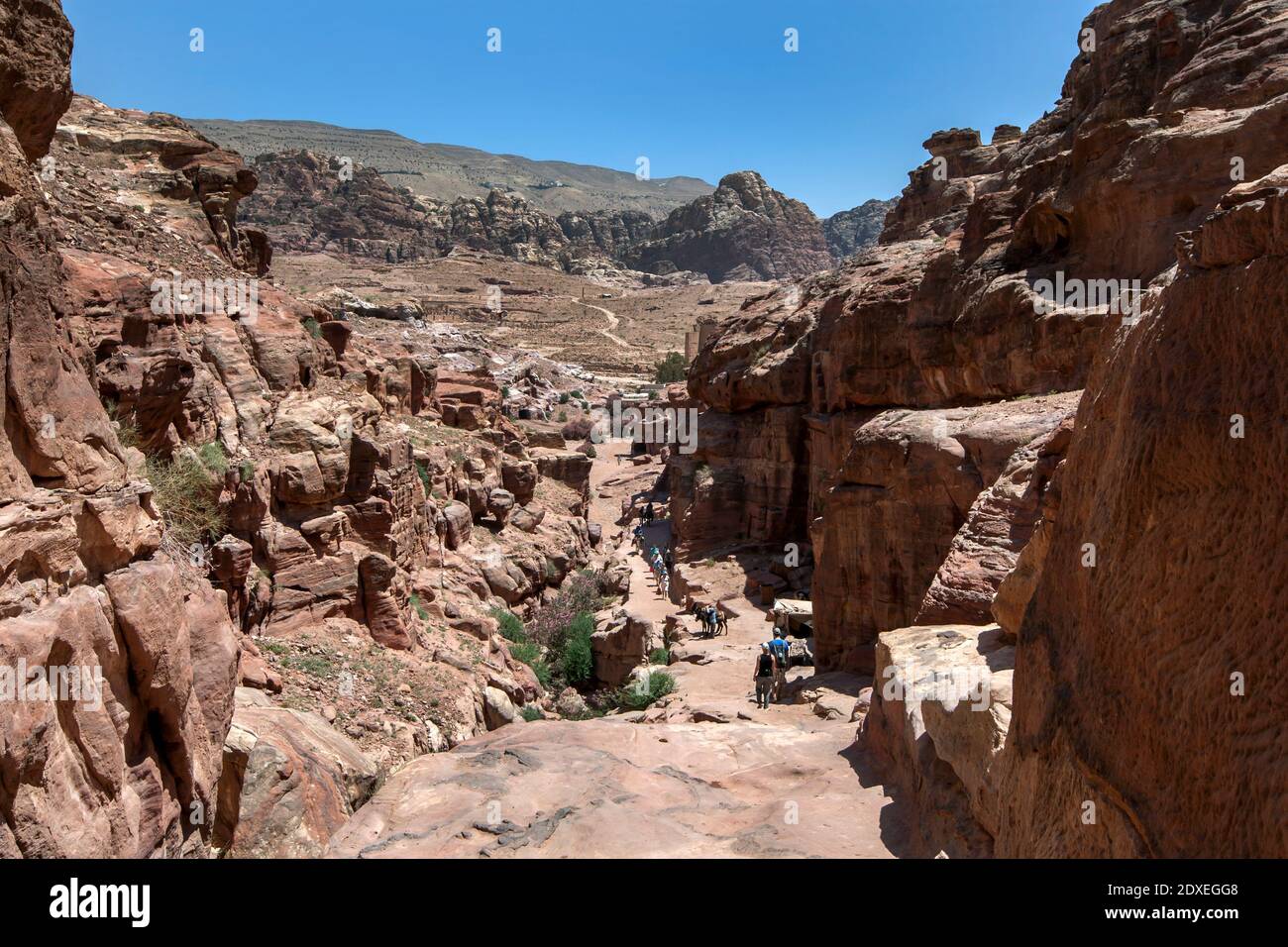 Tourists walking along the rock path through sandstone cliffs leading ...