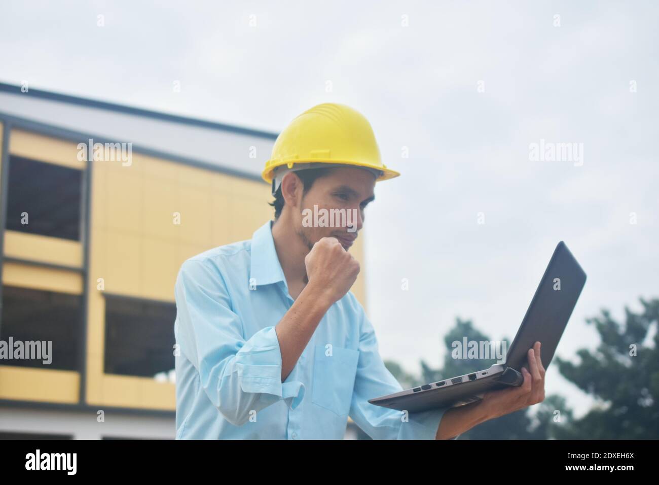 Engineering holding computer notebook with yellow hard hat working ...