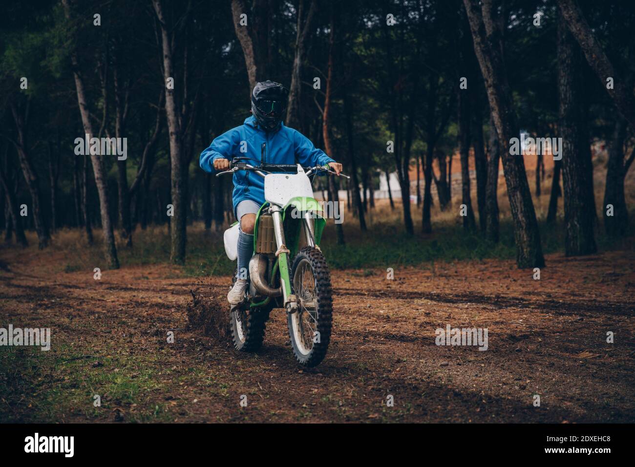 Male teenage boy riding motorcycle on dirt road in forest Stock Photo ...