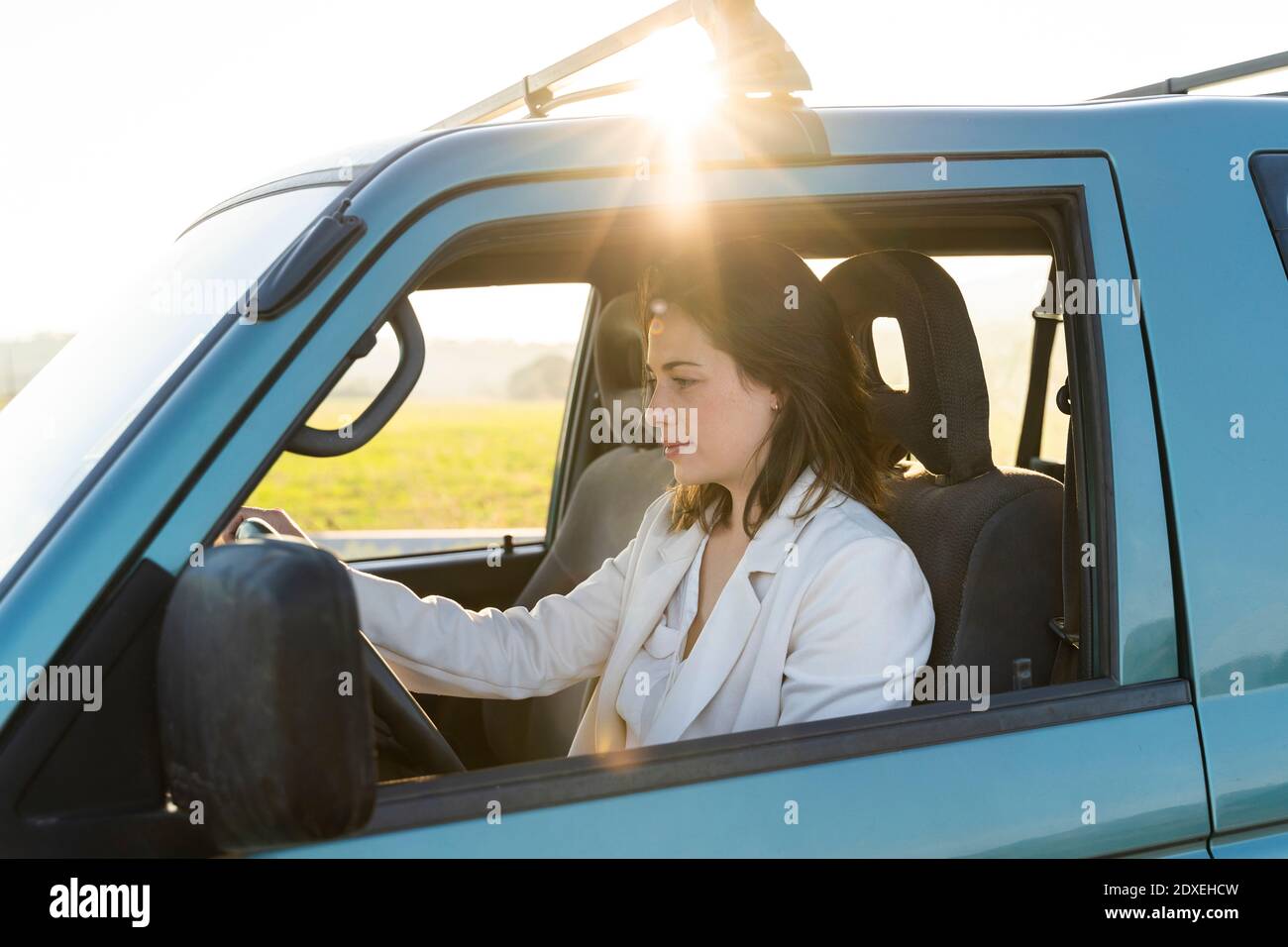 Beautiful woman on road trip driving car during sunset Stock Photo - Alamy