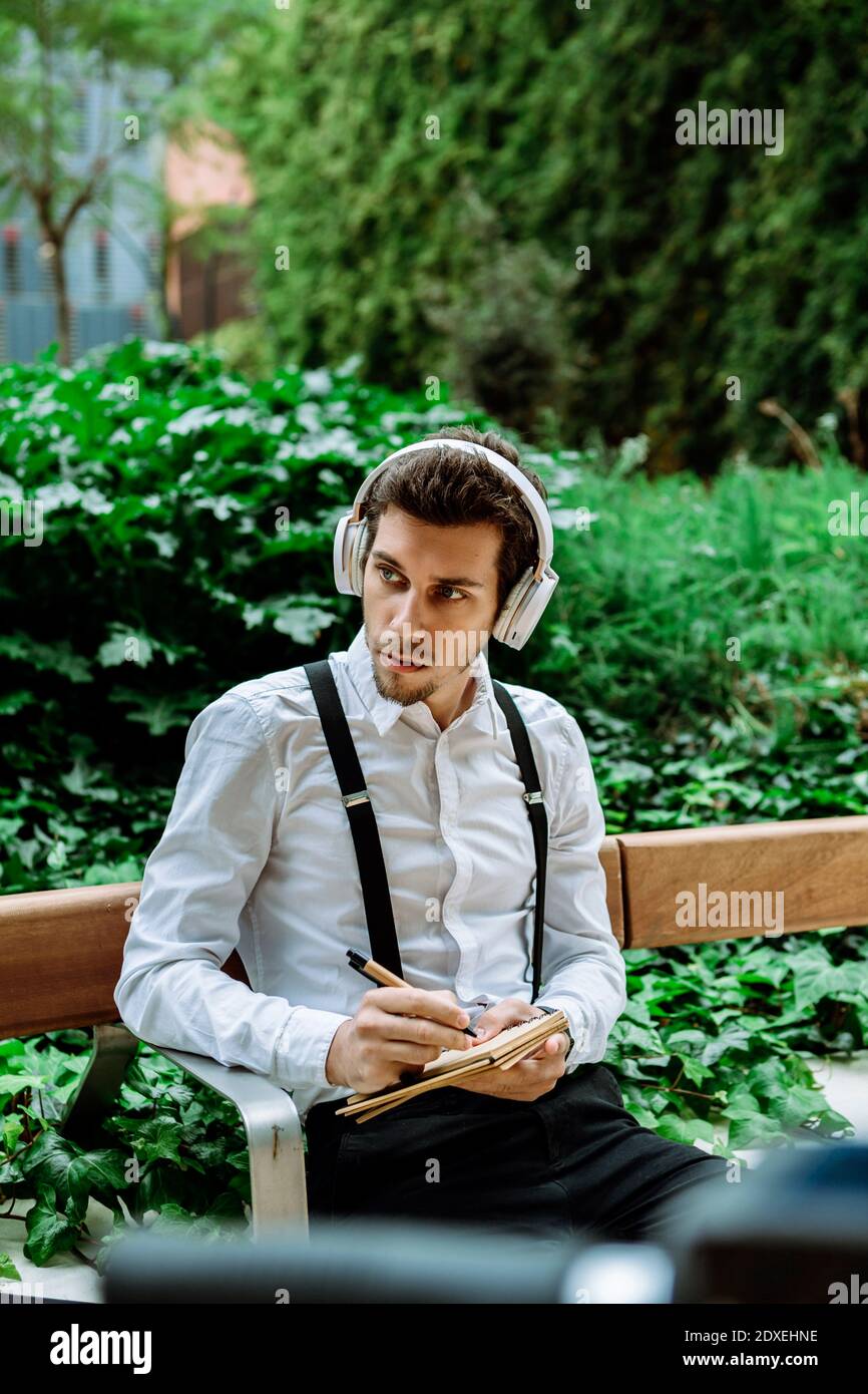 Young man sitting on bench writing on notepad hi-res stock photography ...