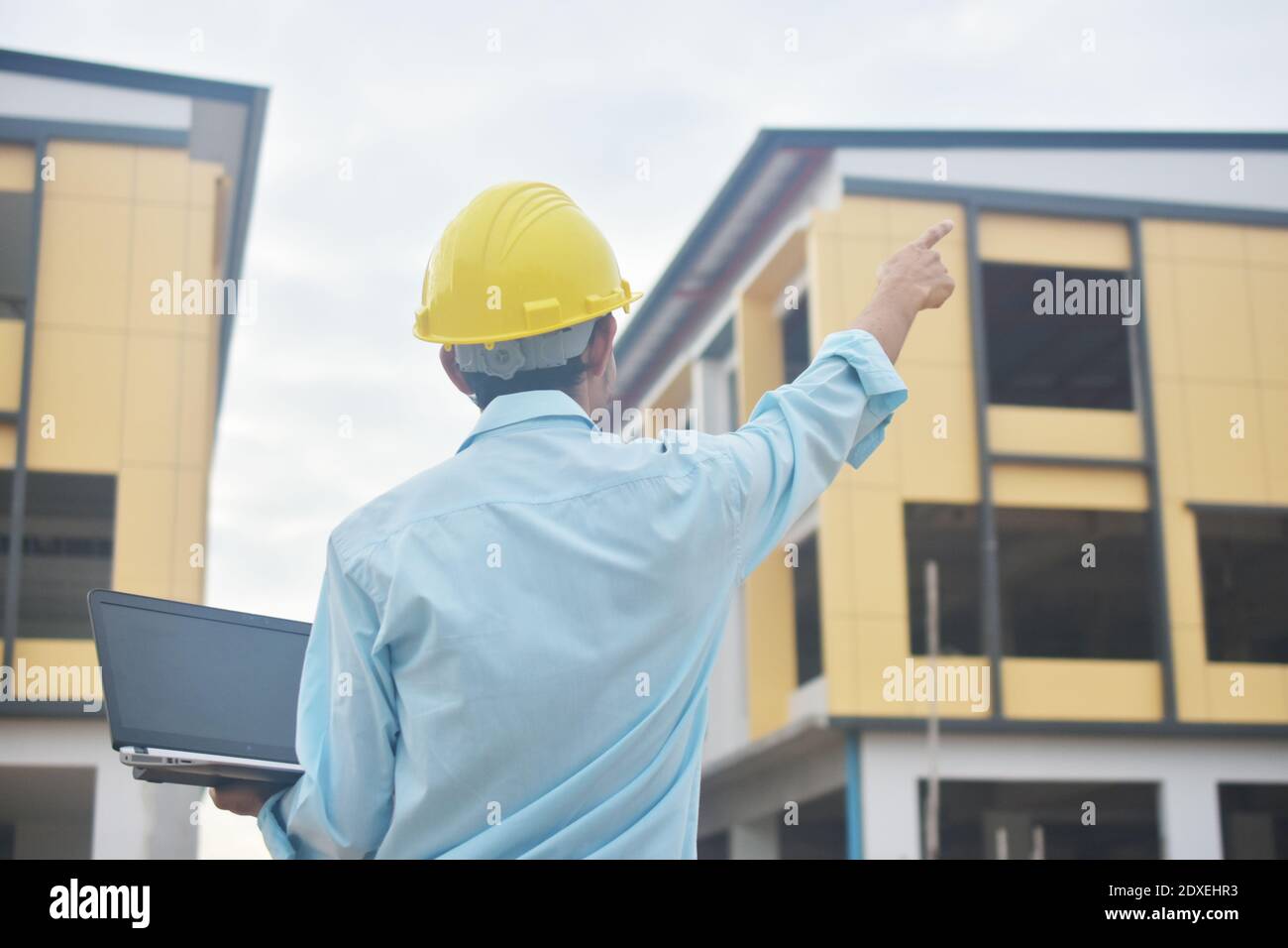 Engineering holding computer notebook with yellow hard hat working ...