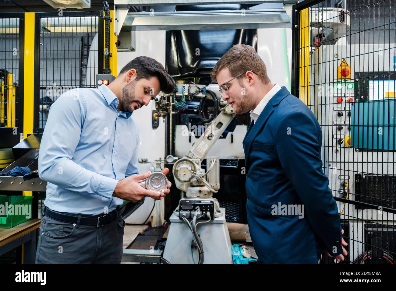 Male colleagues examining machine part in industry Stock Photo - Alamy