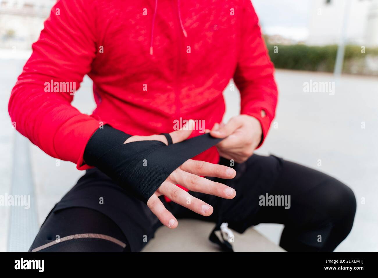 Sportsman tying boxing wrap while sitting on retaining wall Stock Photo ...
