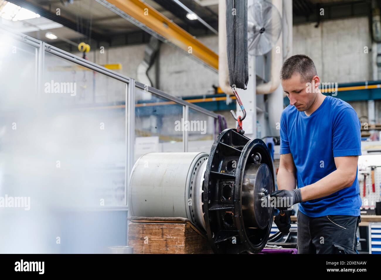 Male engineer fastening nut on machine in illuminated industrial ...