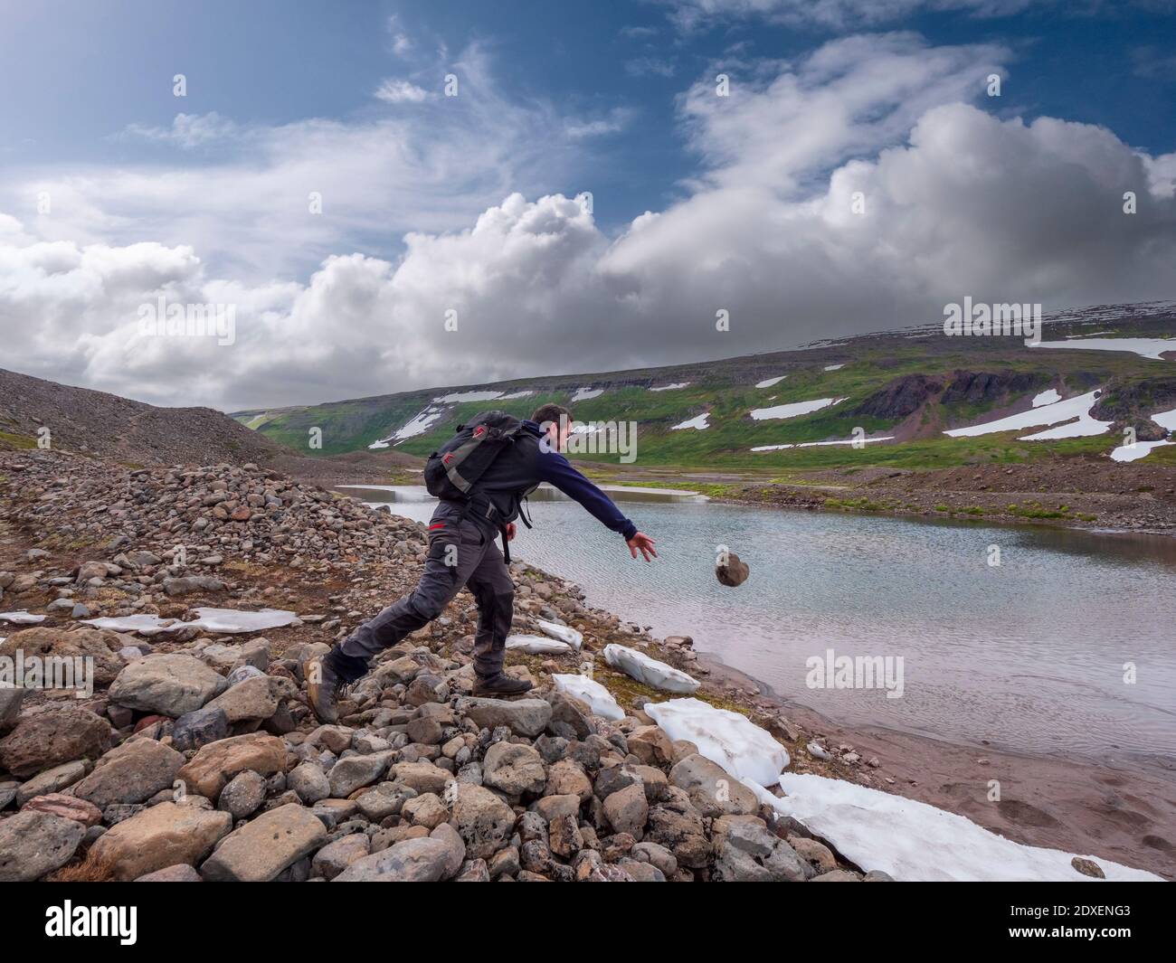 Male hiker throwing rock into river Stock Photo - Alamy