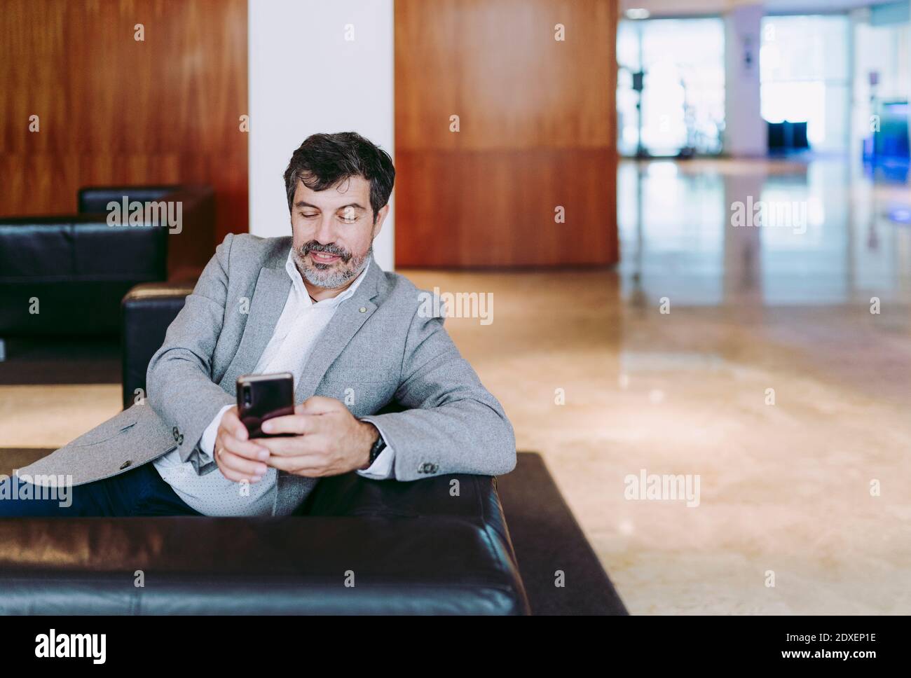 Businessman using mobile phone in hotel lobby Stock Photo - Alamy