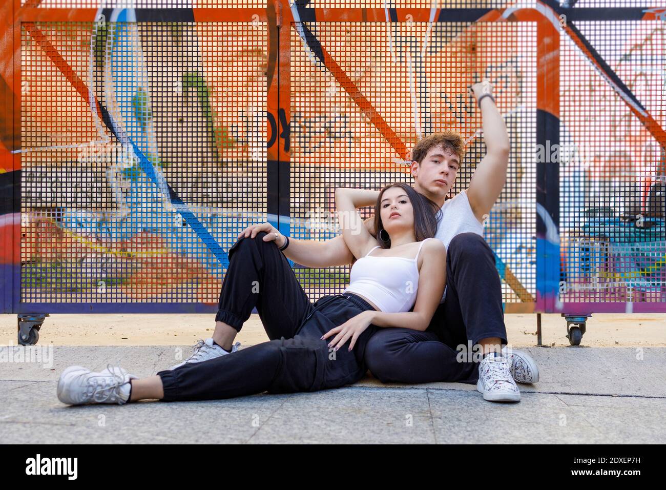 Woman resting while leaning on man sitting against gate Stock Photo - Alamy