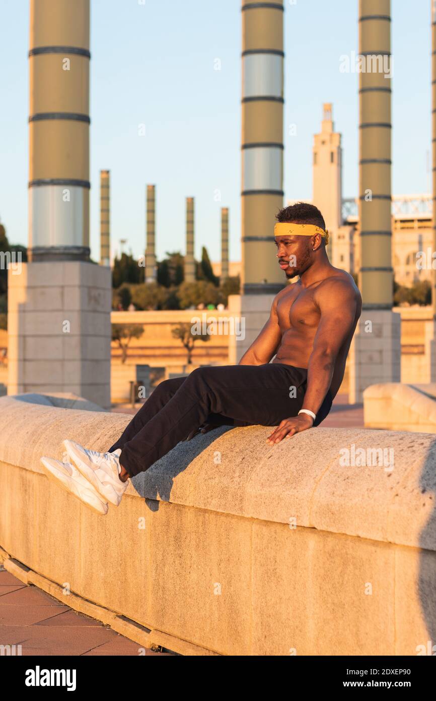 Man doing abdominal muscle exercise while sitting on retaining wall at ...