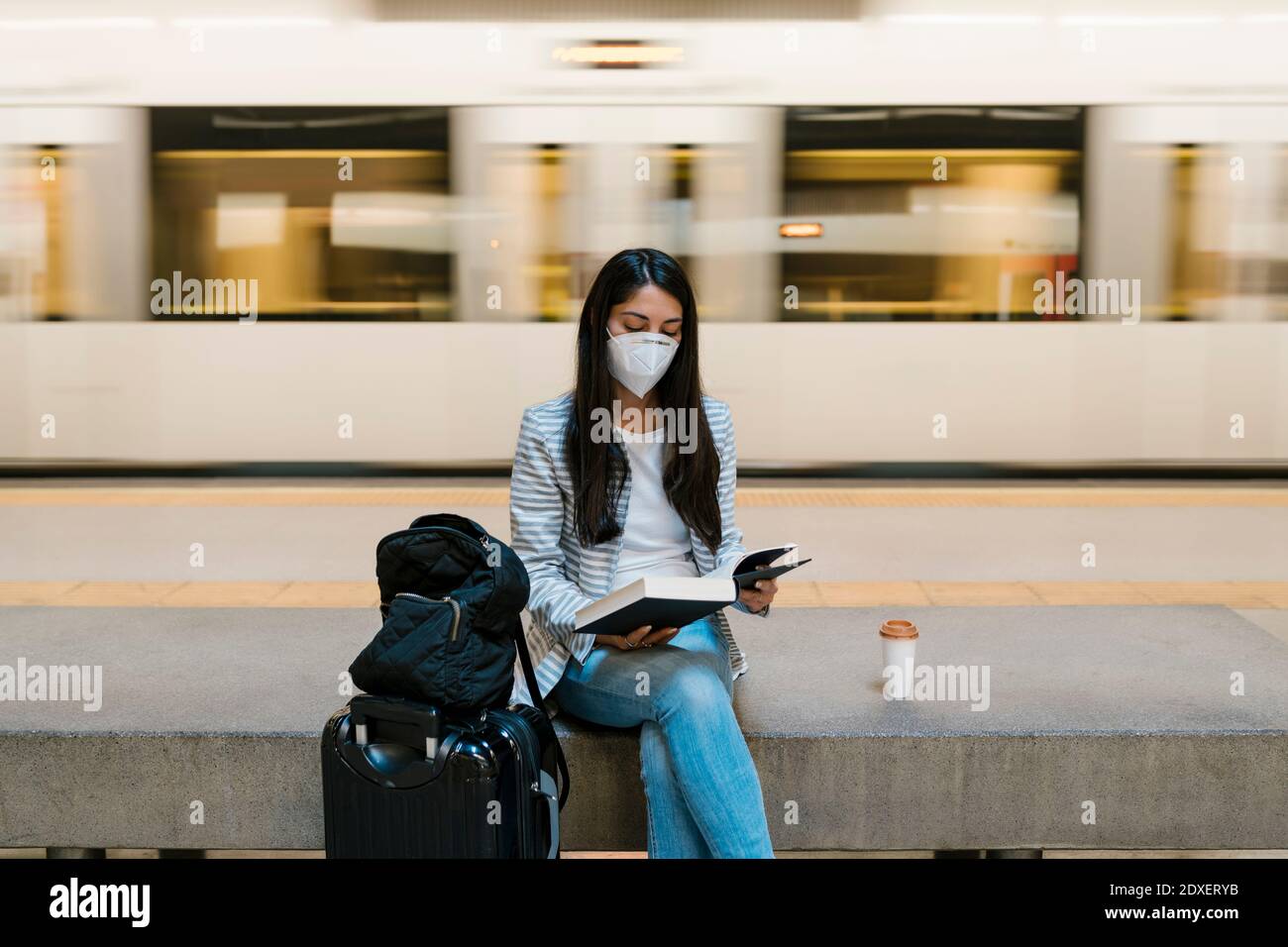 Woman reading book while sitting against moving train at metro station ...