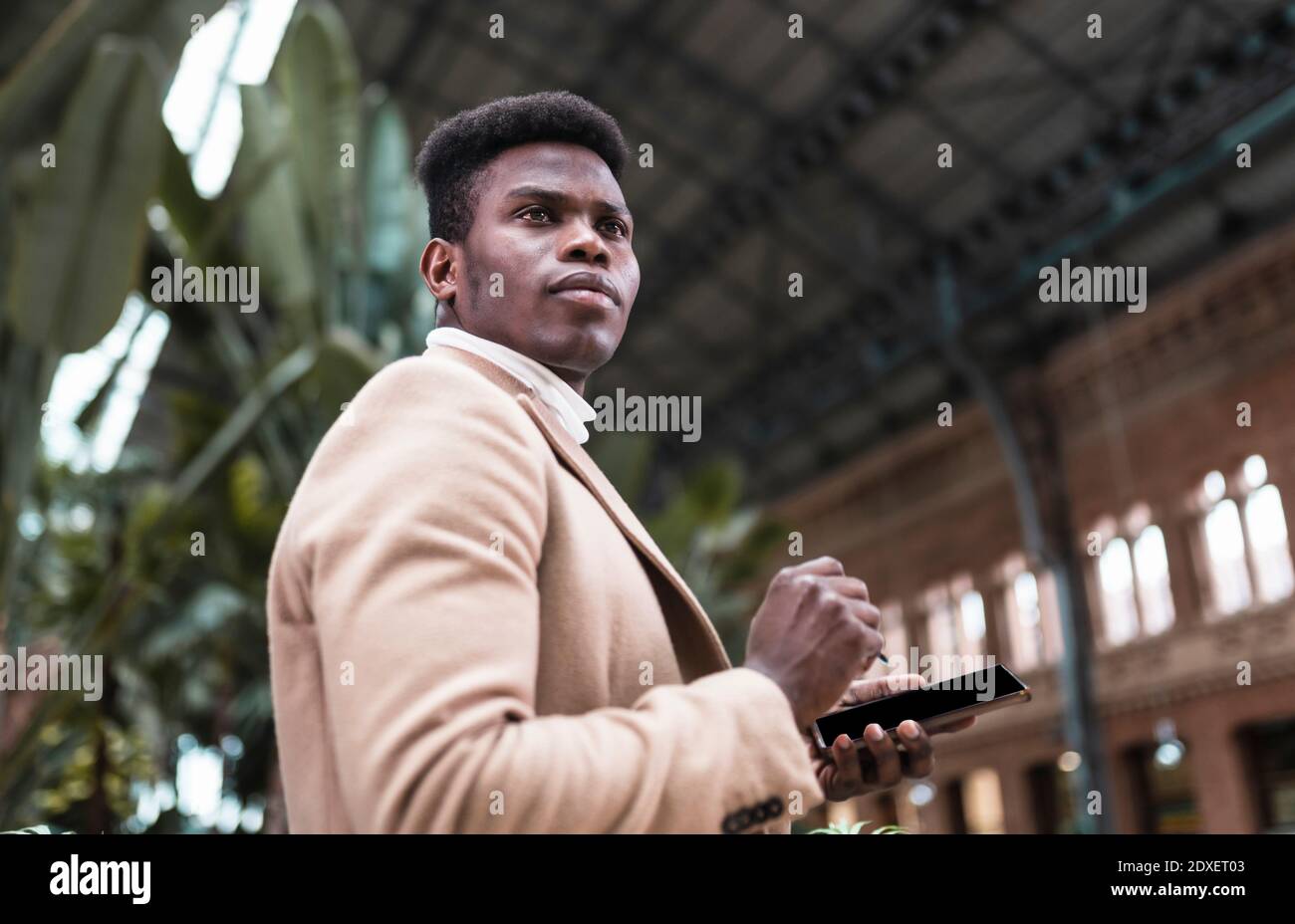 Man using mobile phone while standing at station Stock Photo - Alamy