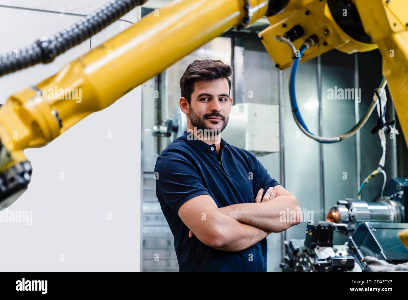 Confident male worker with arms crossed standing in factory Stock Photo ...