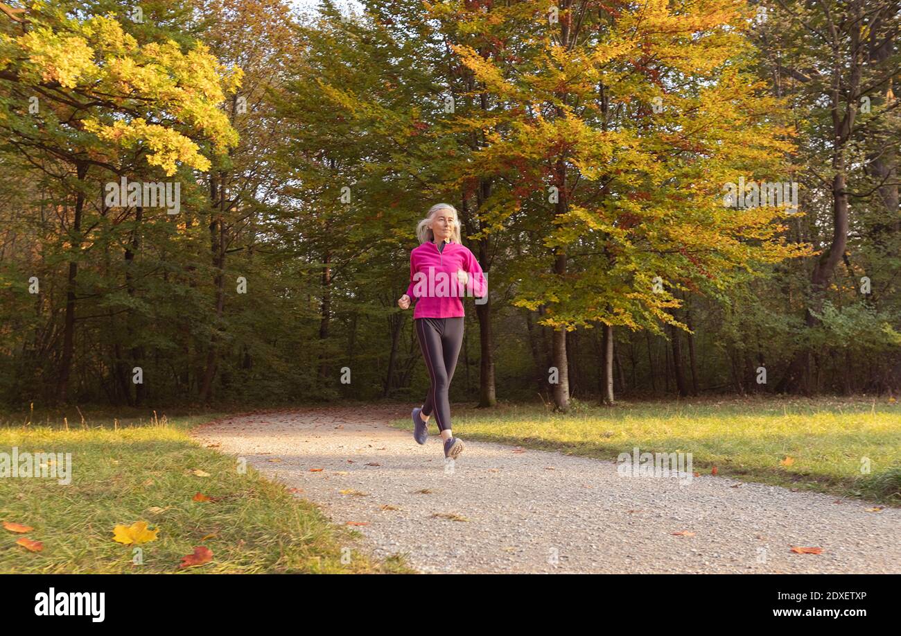 Woman jogging in park against trees Stock Photo - Alamy