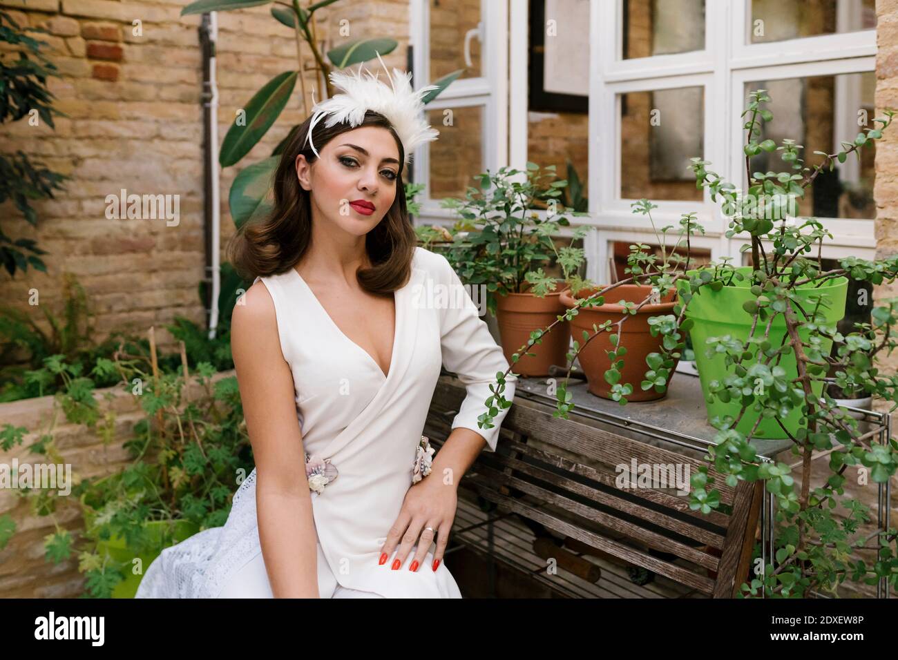 Beautiful bride sitting in garden by plants Stock Photo - Alamy
