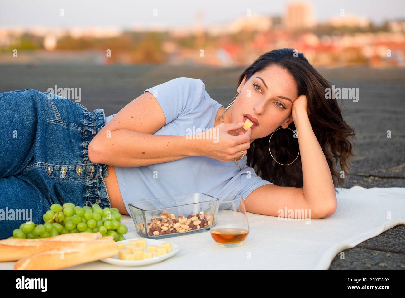 Beautiful woman eating cheese, lying on rooftop at picnic Stock Photo ...